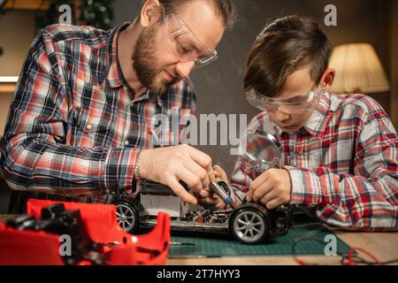 Father teaching his son for soldering and repair remote controlled car ...