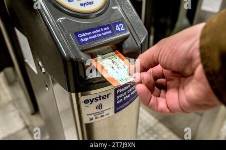 Hand putting train ticket into a TFL stations ticket barrier in Greater ...