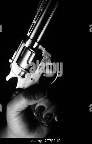 Lady spy detective with painted red nail varnish holding pistol gun at ...