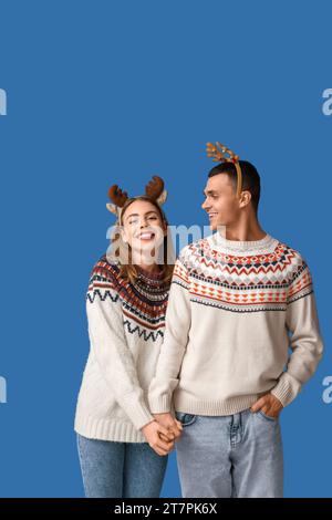 Happy young couple in reindeer horns on red background Stock Photo - Alamy