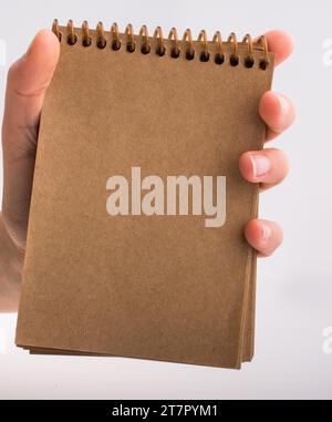 Hand holding brown color notebook on a white background Stock Photo - Alamy