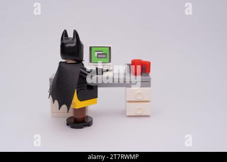 A Lego figurine of Batman sitting on a computer desk made of Lego ...