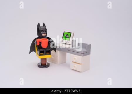 A Lego figurine of Batman sitting on a computer desk made of Lego ...