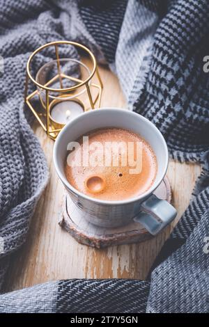Composition with warm plaid, book, cup of hot drink on color carpet ...