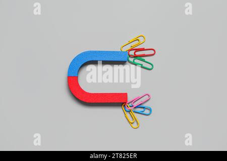 Magnet attracting paper clips on beige background Stock Photo - Alamy