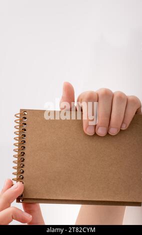 Hand holding brown color notebook on a white background Stock Photo - Alamy