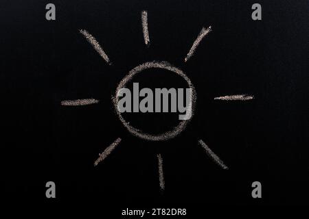 Hand drew sun by chalk with light ray shape on blackboard background ...