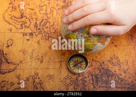 Compass on map beside a globe under hand Stock Photo - Alamy