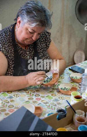 An artisan hand paints traditional Alentejo pottery at Olaria O Patalim ...