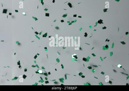 Shiny green confetti falling down on light grey background Stock Photo ...