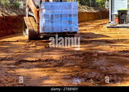 Worker at small forklift unloading lifts pallet concrete blocks for ...