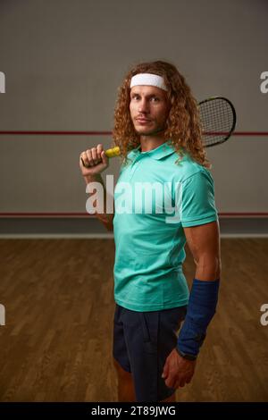 Portrait of male squash player standing with racket ready for game ...