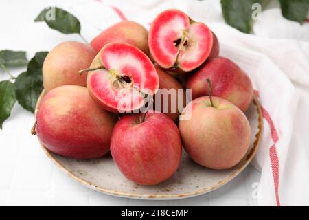 Tasty apples with red pulp and leaves on white tiled table, flat lay ...