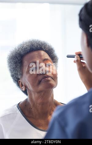 African american female doctor testing eyes of senior female patient in ...