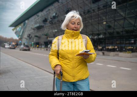 Tourist is waiting a taxi. Senior woman stand outside airport and wait ...