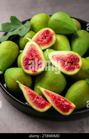 closeup of some ripe figs on a gray textured surface, next to a wooden ...