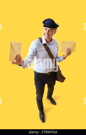 Mature postman with envelopes on yellow background Stock Photo - Alamy