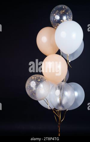 A bunch of balloons in white, beige and transparent colors on a dark ...