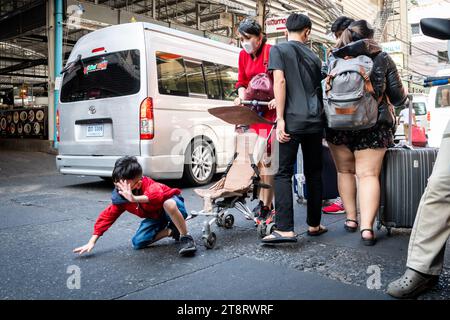 A young boy takes a tumble falling from his pram in the busy streets of ...