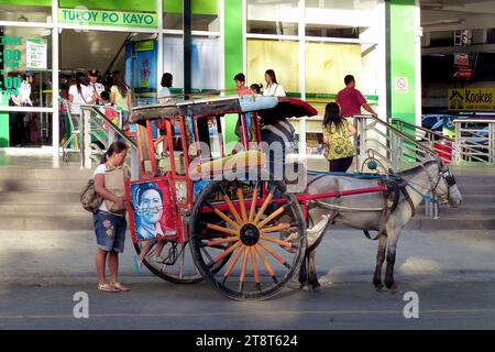 A horse drawn carriage known as a Kalesa being driven in downtown Cebu ...