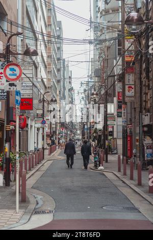 A narrow city street illuminated by vibrant colorful light projections ...
