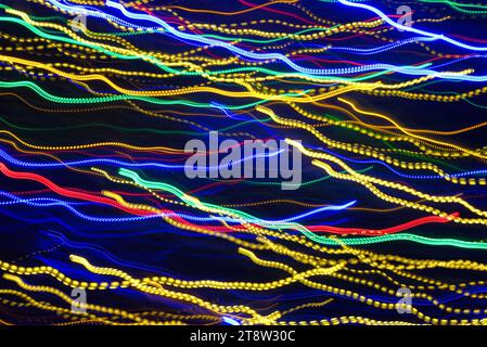 Blurred multi coloured light patterns streaks against a dark background ...