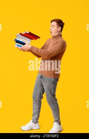 Emotional man holding stack of books on green background Stock Photo ...