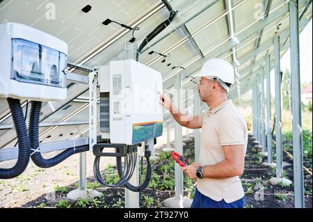 Male worker checking if solar inverter working right. Young man ...
