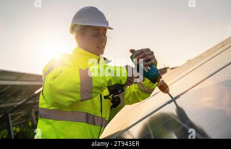 Technician assembling solar panels with a cordless drill at a solar ...