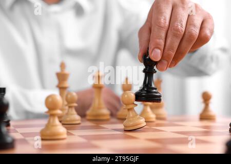 Man moving chess piece at checkerboard against light blue background ...