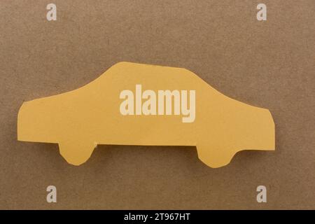 Car shape cut out of yellow paper on brown background Stock Photo - Alamy
