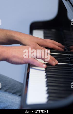 Human hands playing the keys notes and chords on a classic black piano ...