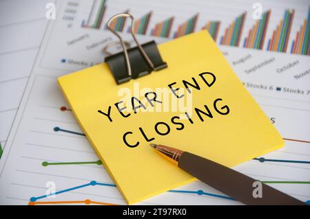 Year end closing text on sticky note and stuck to a calendar background ...