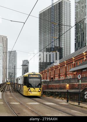 Manchester Bee Network Metrolink tram travels past the tall skyscrapers ...