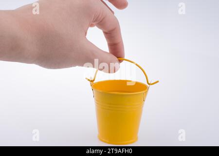 Hand holding a yellow bucket on a white background Stock Photo - Alamy