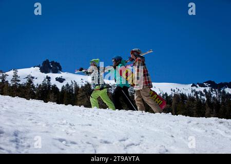 Three friends walking with skis and snowboard at a ski resort Stock ...