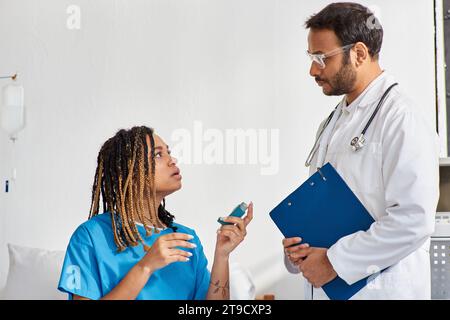 young indian doctor teaching his ill african american female patient ...