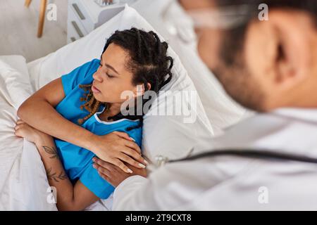 cropped view of indian doctor comforting his ill sad african american ...