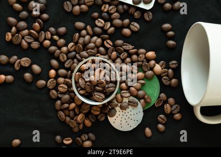 Coffee beans inside and around a refillable coffee capsule on a black ...