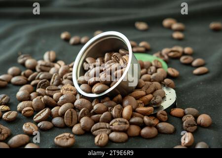 Coffee beans inside and around a refillable coffee capsule on a black ...