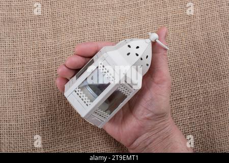 Old retro styled lantern in hand on canvas Stock Photo - Alamy