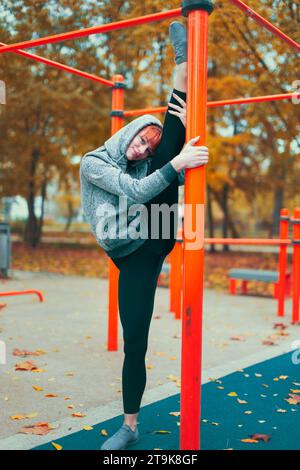 Young gymnast urban Caucasian woman at playground hanging upside down ...