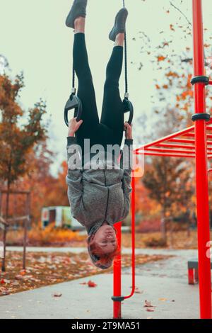 Young gymnast urban Caucasian woman at playground hanging upside down ...