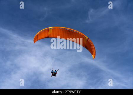 A tandem paraglider flies overhead at the GGBY World Highline Festival ...