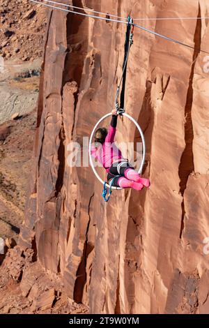 Aerial acrobat performs suspended in chains wearing a colorful bodysuit ...