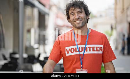 Young hispanic man activist wearing volunteer uniform touching chest ...