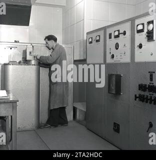 1950s historical picture of a control room with worker sitting at ...