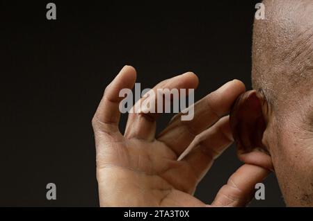 suffering from deafness and hearing loss on grey black background with ...