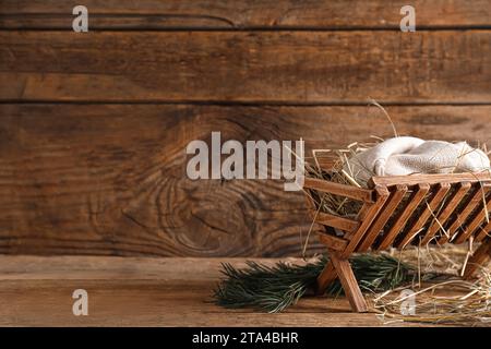 Bible, wooden manger with hay and dummy of baby on snow against black ...