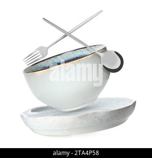 Clean dishes and fork falling on white background Stock Photo - Alamy